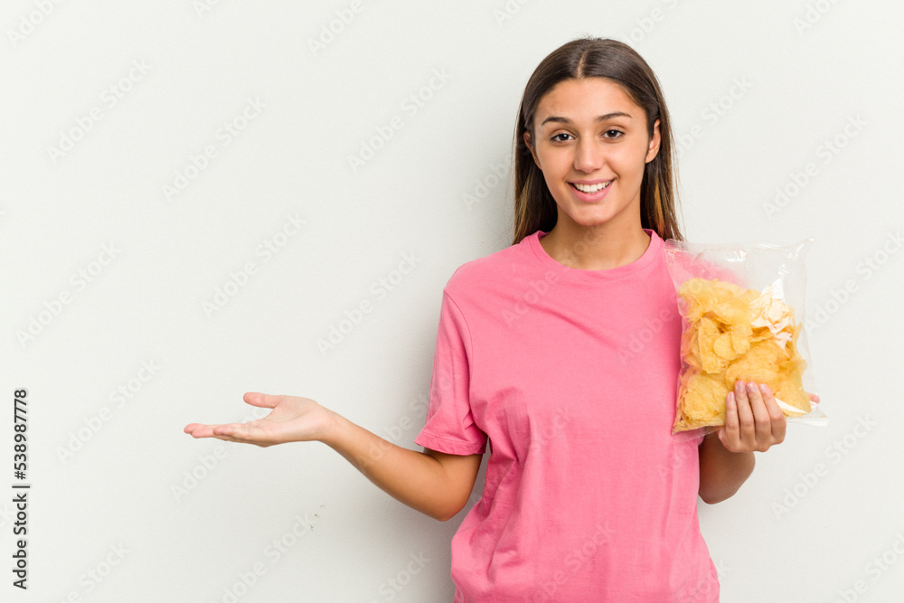 Young Indian woman holding crips isolated on white background showing a ...