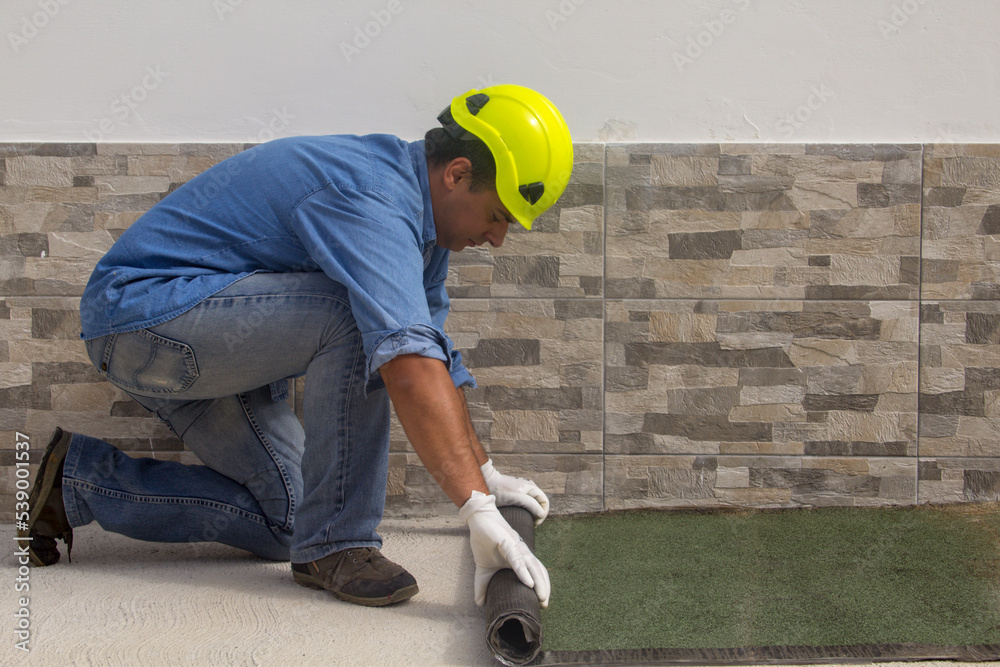 Construction worker at work while unrolling the tarred bituminous ...