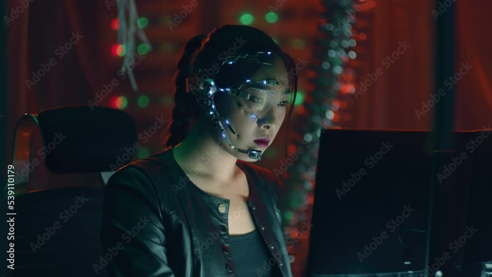 Focused cyberpunk girl in black leather jacket works on the computer ...