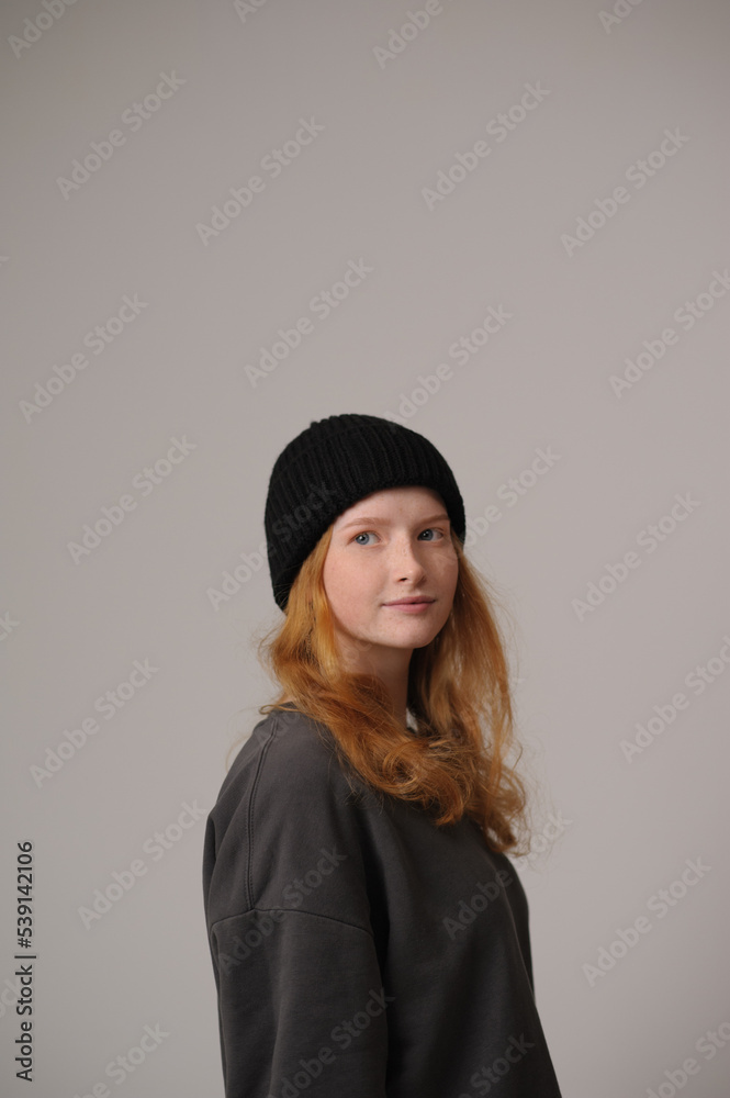 young girl model in black cap and grey jackett isolated on grey ...