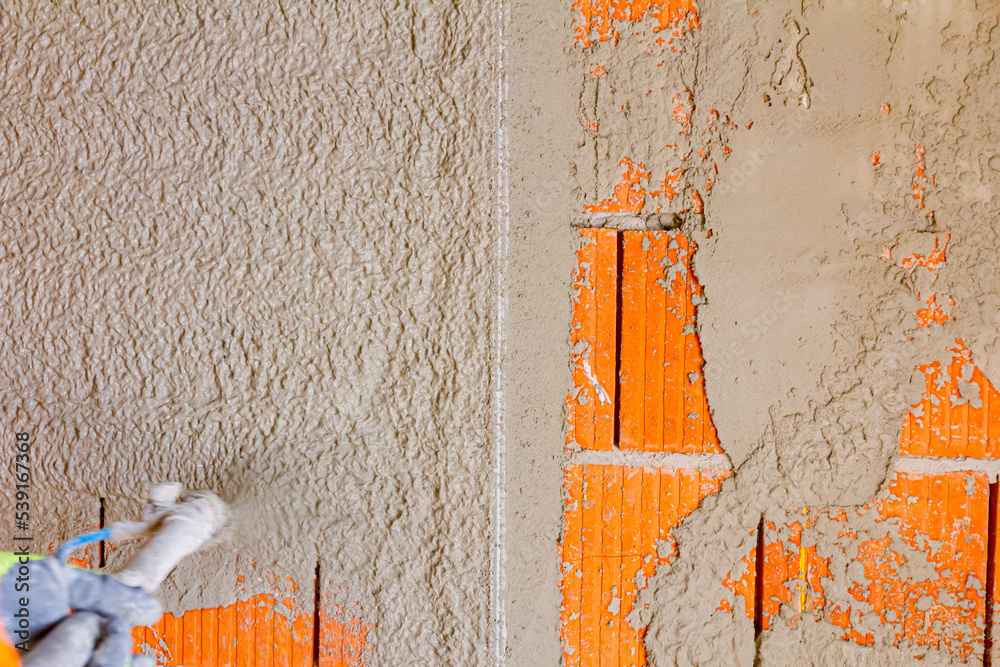 Craftsman holds mortar hose for plastering walls at indoor of ...