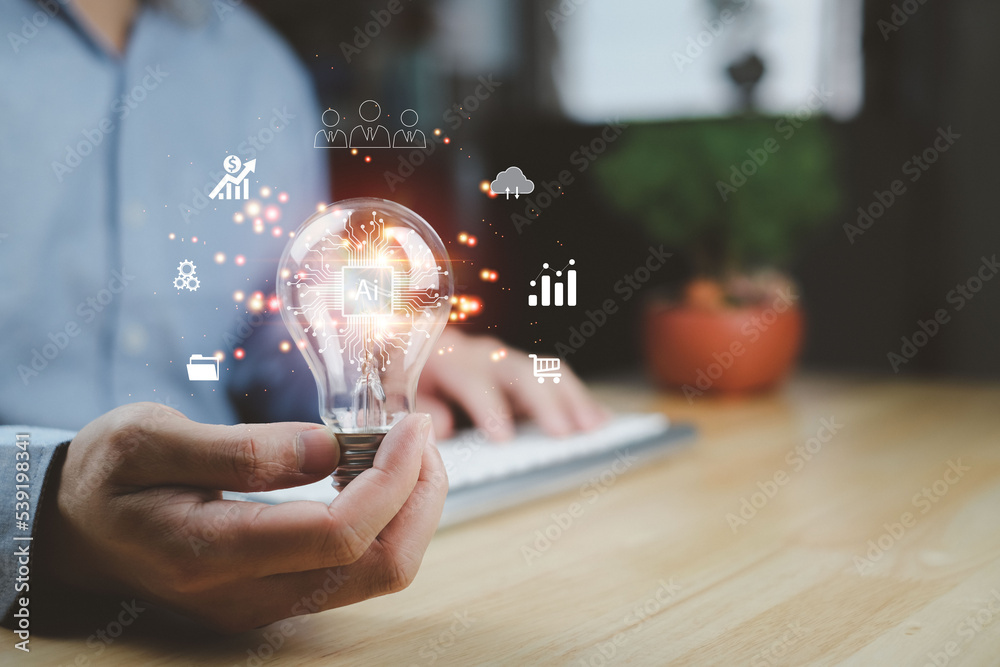Businessman's hand with light bulb and gear AI icon in it. And he uses ...