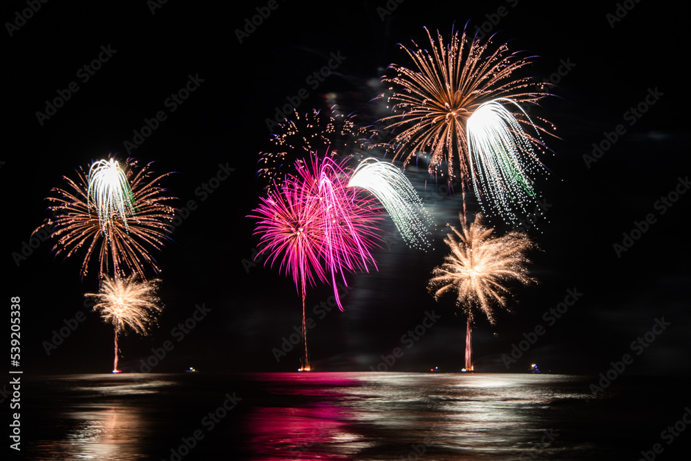 Multi coloured fireworks exploding over an ocean in the night sky ...