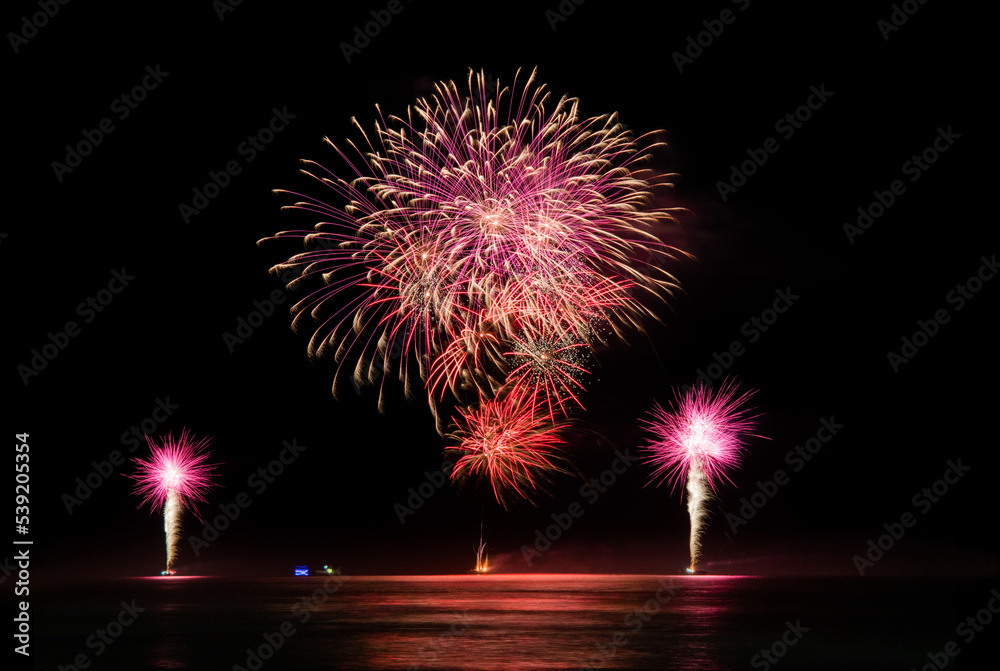 Multi coloured fireworks exploding over an ocean in the night sky ...