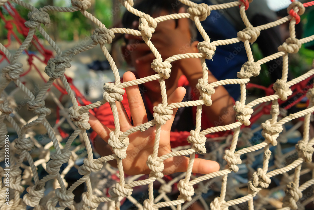 Little boy showing hand signal in rope net to stop. Stop abusing, fear ...