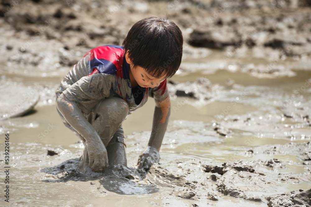 cute happy asian little boy enjoying to play in the mud at playground ...