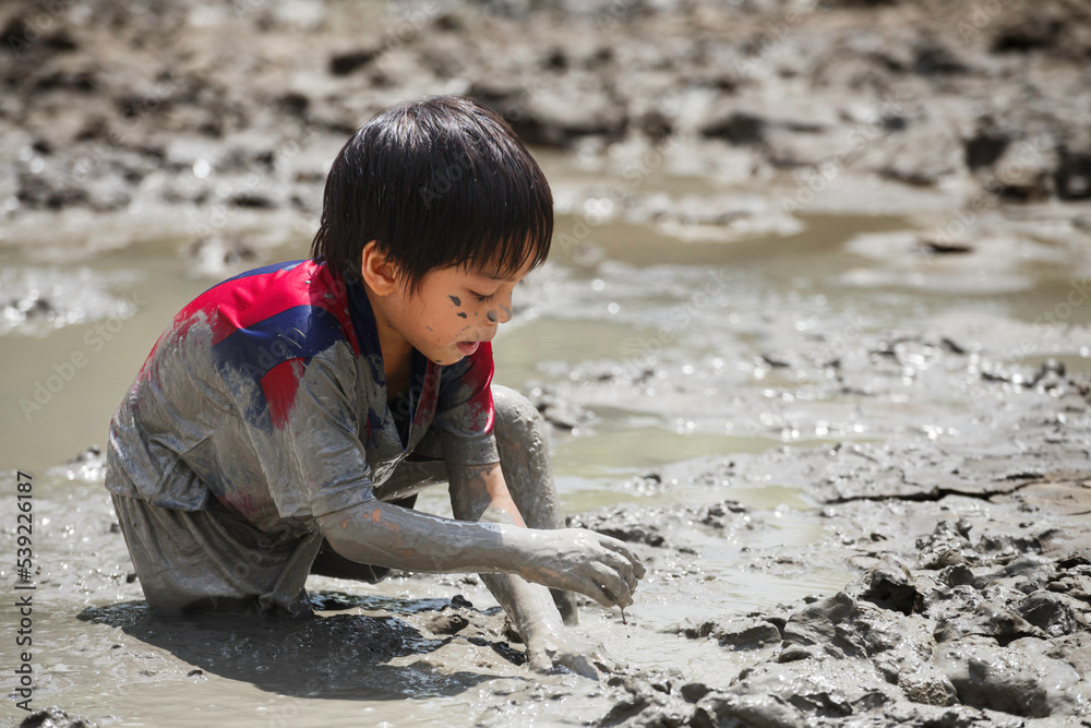 cute happy asian little boy enjoying to play in the mud at playground ...