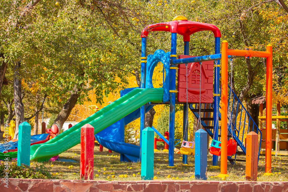 Bright playground in the park. Playground with slides and swings for ...