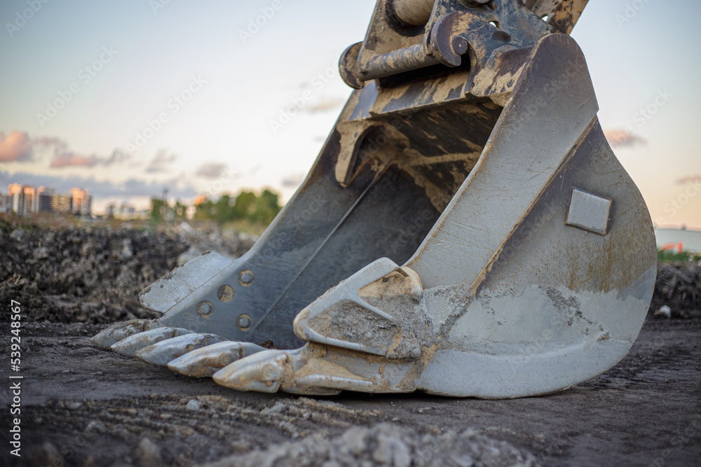 The metal bucket of a parked excavator lies on the ground soiled after ...