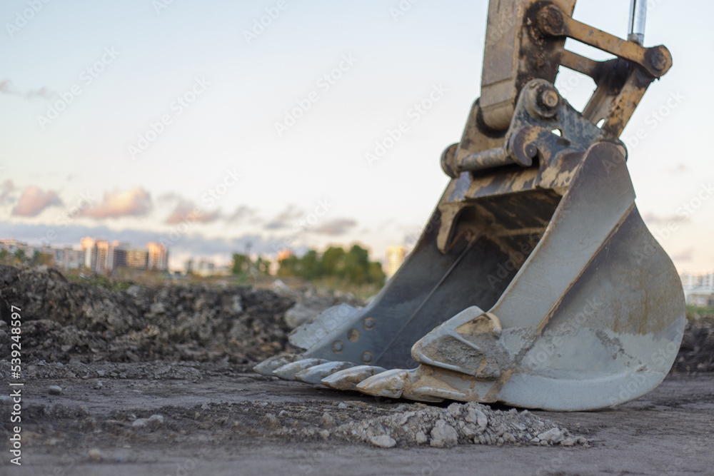 The metal bucket of a parked excavator lies on the ground soiled after ...