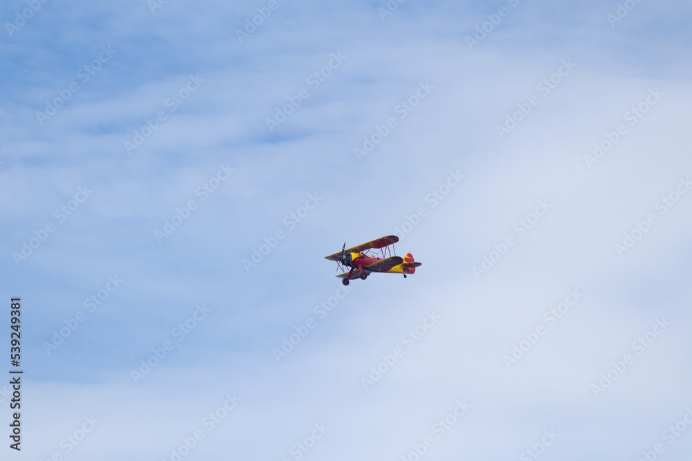 Little red biplane flying across semi cloudy sky. This plane almost ...