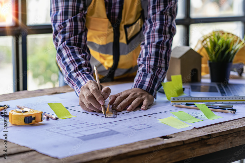 A close-up view of engineers drawing plans and measurements at work ...