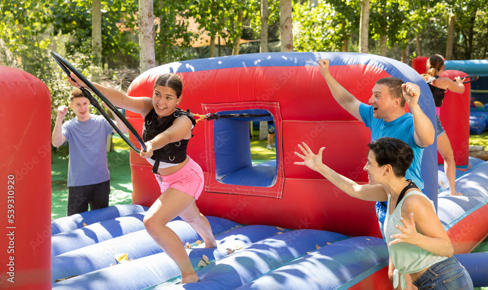 Caucasian girl playing tug of war game with hoop on inflatable ...