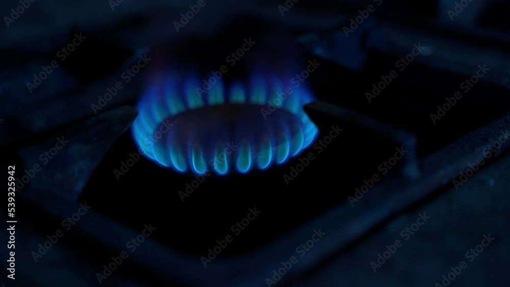 A blue flame burns unsteadily in a gas cooker at a cold color ...