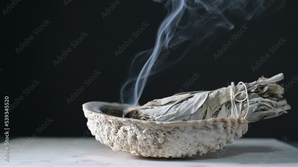 Burning sage in a shell on a wood table with black background showing ...