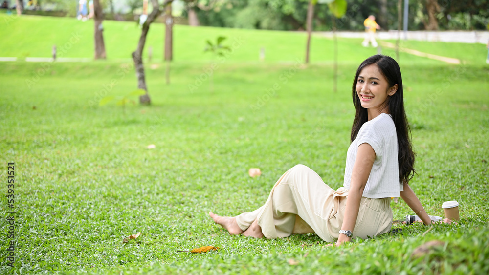 Attractive Asian female sitting on green grass in beautiful and amazing ...
