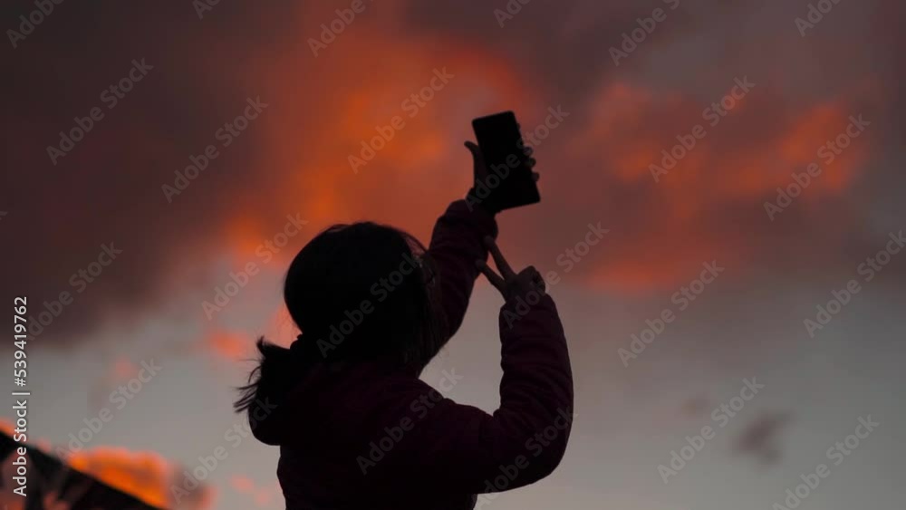 Silhouette of Indian female holding mobile phone and posing for selfie ...