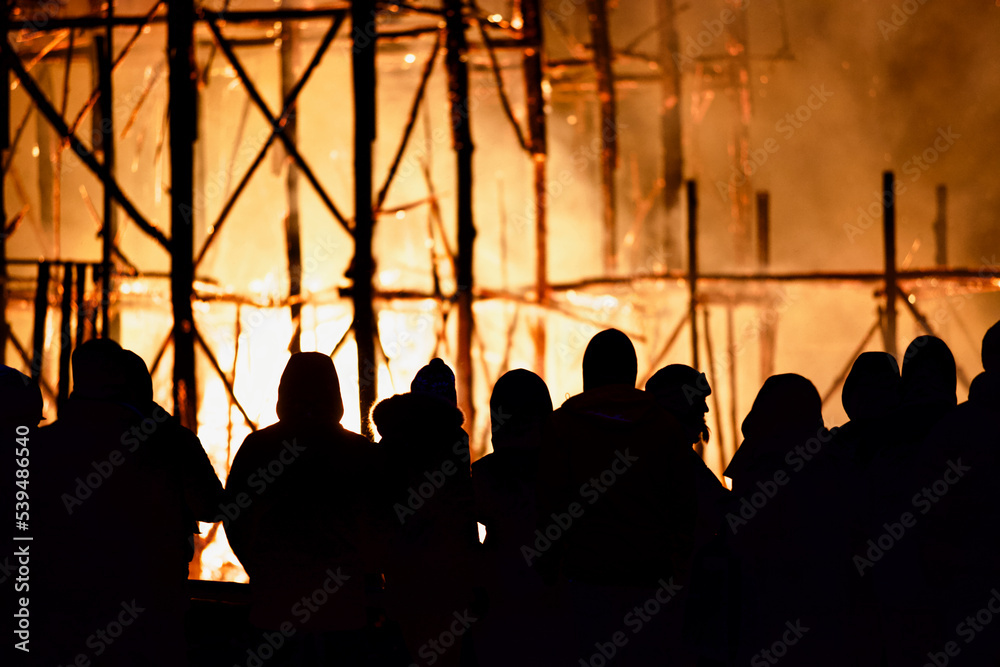 Dark silhouettes of people against the backdrop of a giant raging fire ...