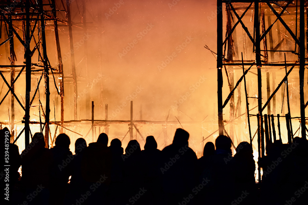 Dark silhouettes of people against the backdrop of a giant raging fire ...