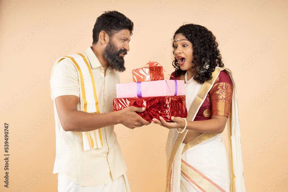 Happy South indian couple wearing traditional dress holding Gift boxes ...