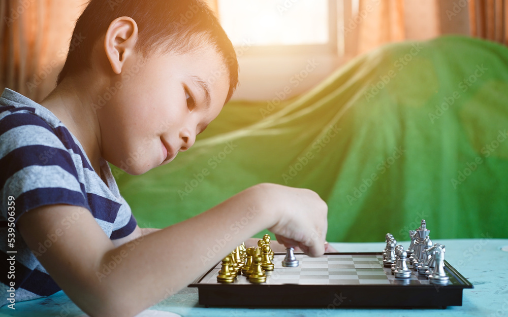 Cute little boy playing chess. Young boy intensely develops chess ...