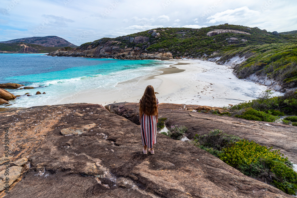 aerial view of a girl in a long dress walking on a small hidden ...