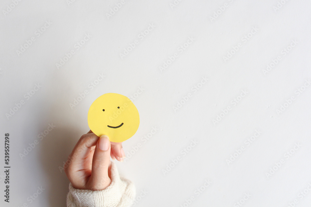 Woman hands holding yellow smile face paper on white background, top ...