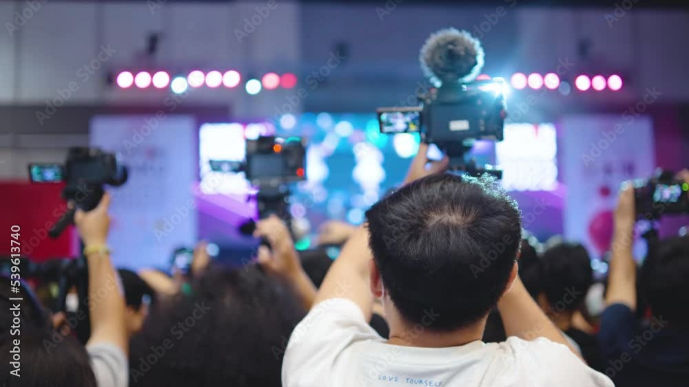 Rear view of man hands taking recording video of live music concert ...