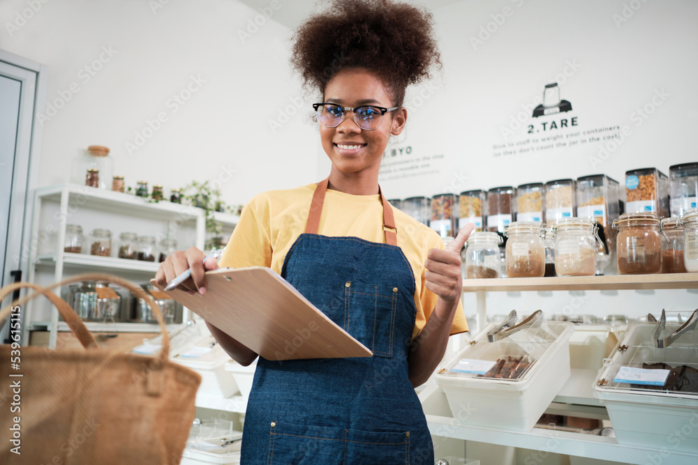 Portrait of young Black female shopkeeper smiling and looking at camera ...