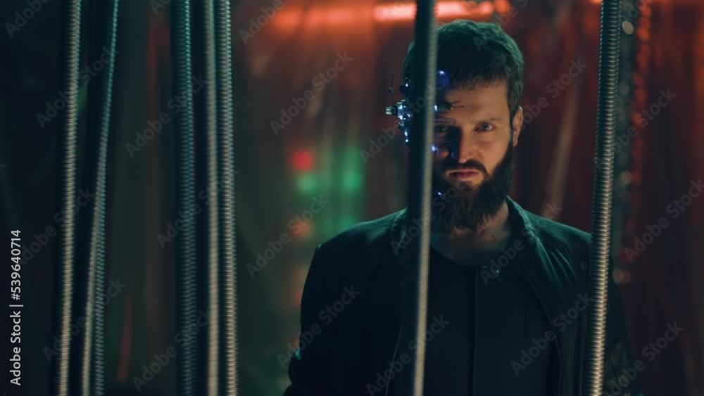 Young brunette guy in Cyberpunk style stands behind the black rods ...
