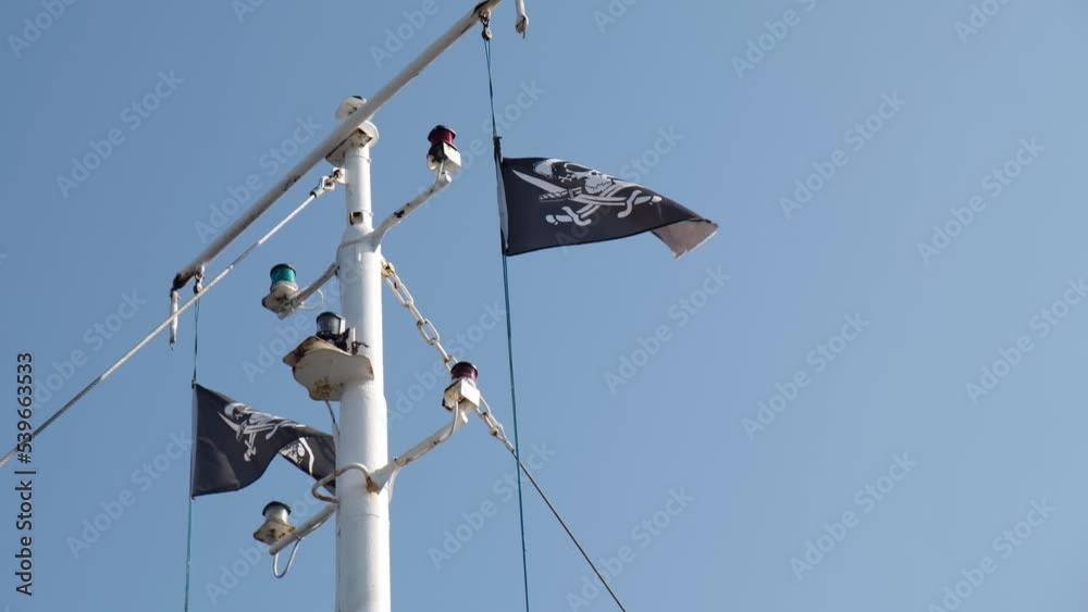 Jolly Roger or pirate ship flag waving with flagpole and blue sky ...