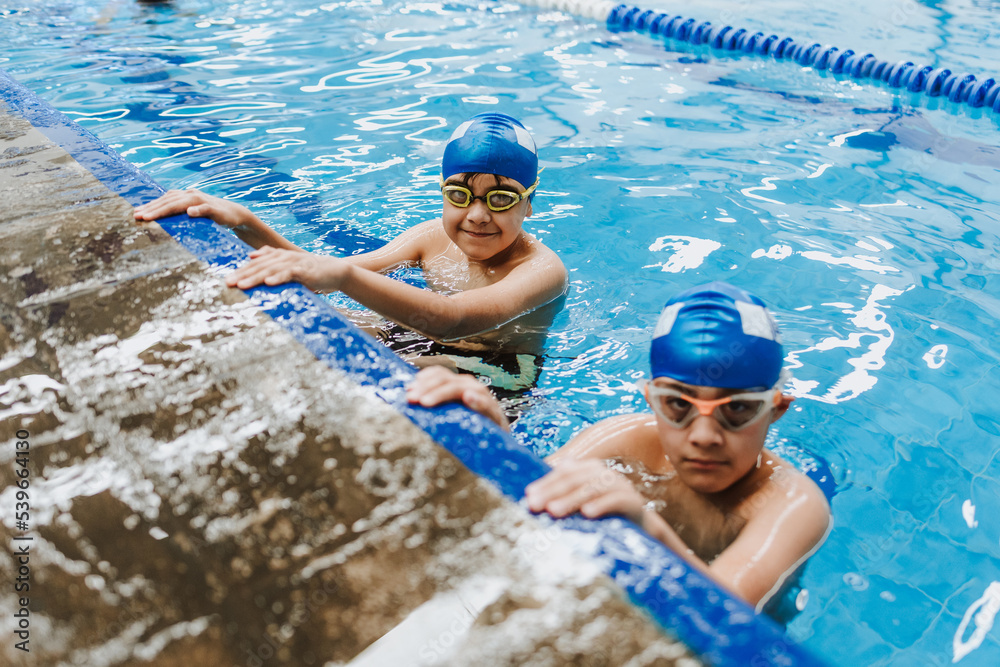 latin child boy swimmer wearing cap and goggles in a swimming training ...