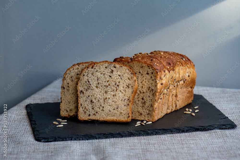 Rye bread with seeds lies on a dark board on a light table. My home ...