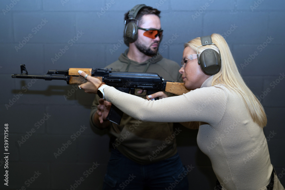 The girl is training to shoot from the ak 47 in the shooting range with ...