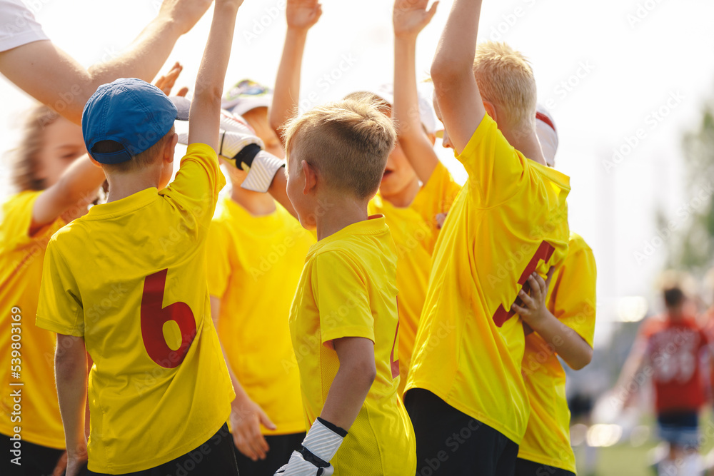 Foto de Happy kids sports team stacking hands at the field. Motivated ...