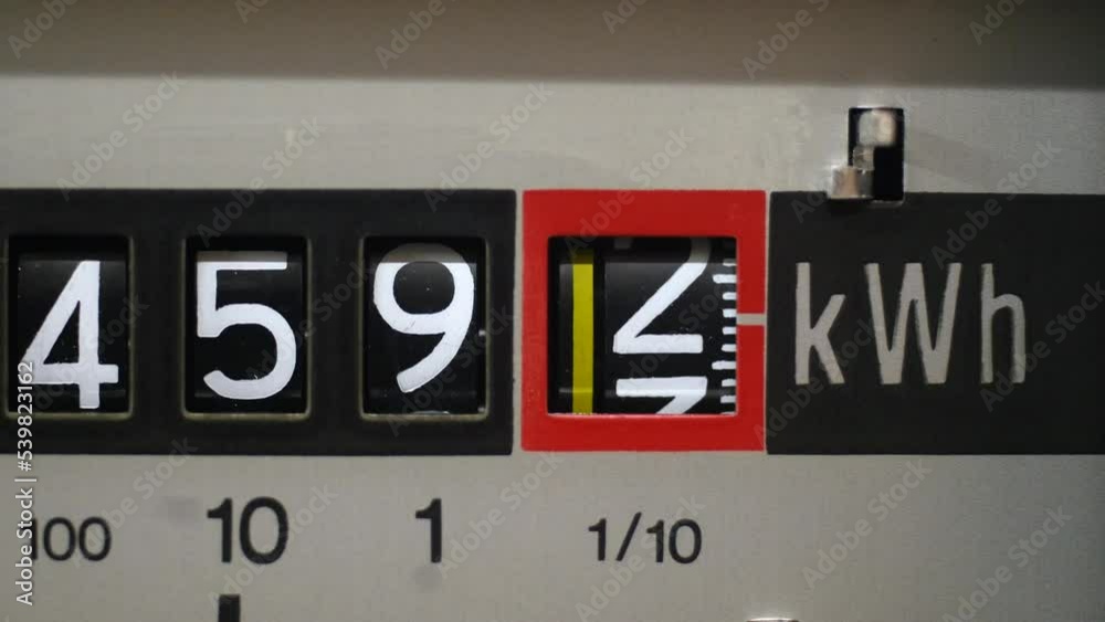 Close up of an electric meter with fast turning measuring red dial ...