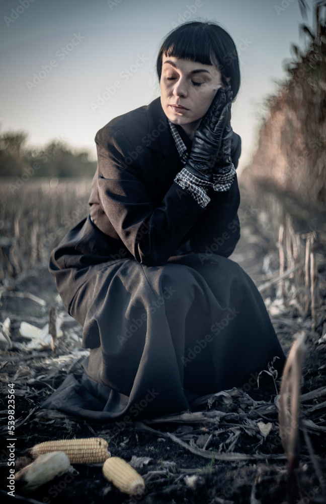 On an autumn evening, a girl in a black business suit stands in a field ...