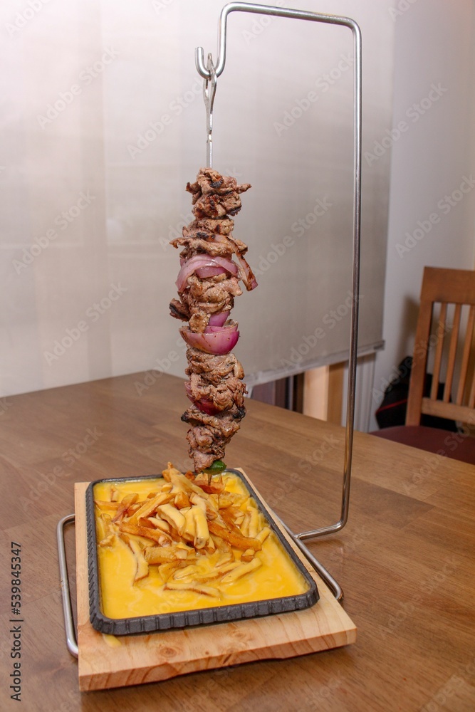 Hanging Espetada with onions and French fries Stock Photo | Adobe Stock