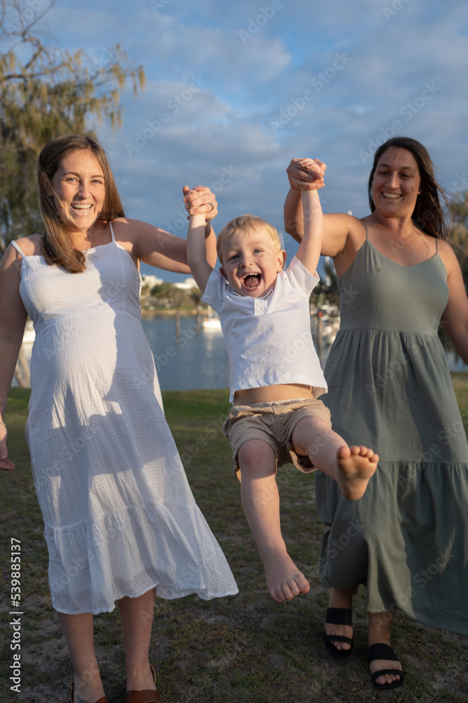 Lesbian family swinging child in park Stock Photo | Adobe Stock