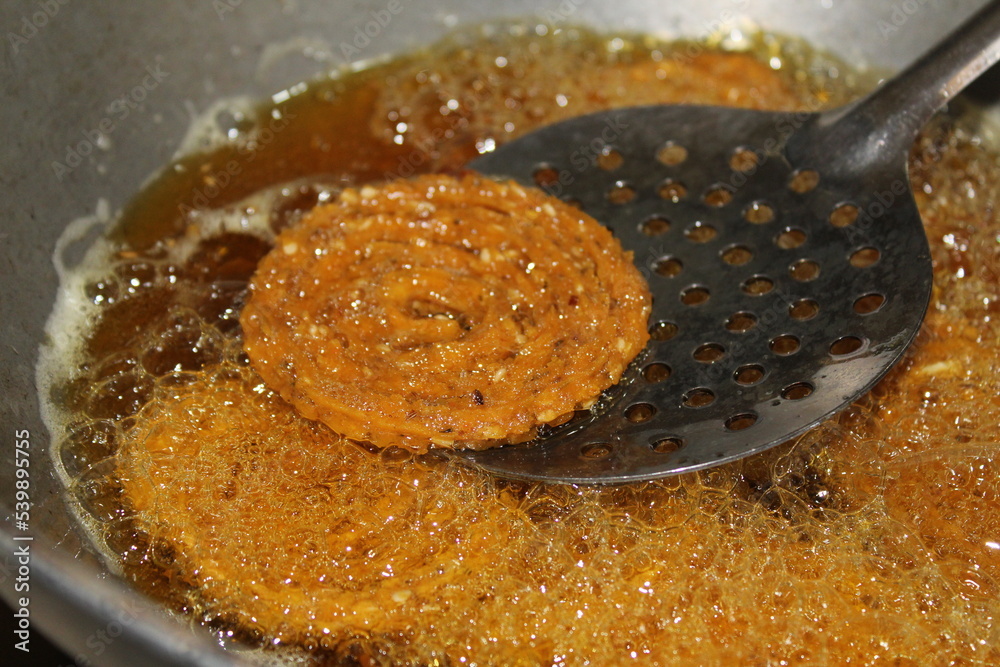Chakali frying in oil, Indian Traditional Tea Time Snack Chakli, a deep ...