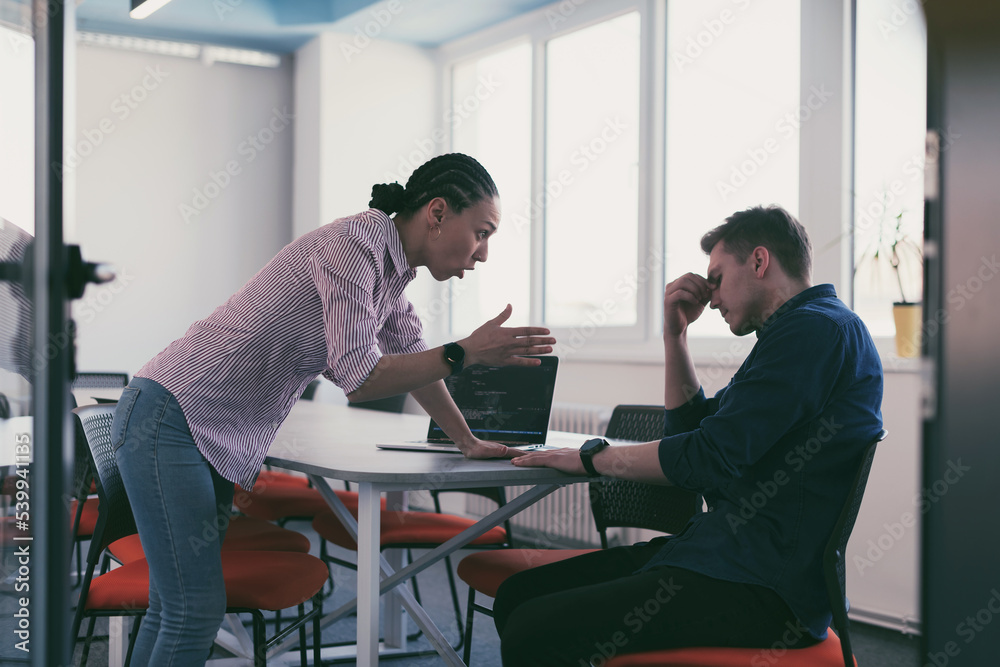 Emotional couple of young colleagues arguing in modern office. African ...