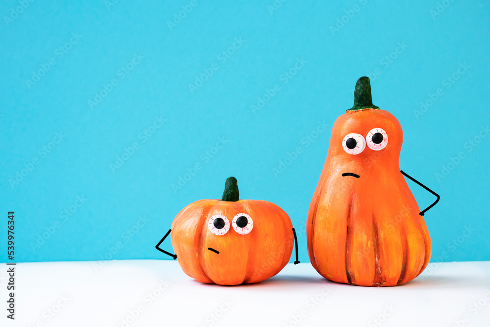 Two pumpkins with funny faces, bulging eyes and thin handles on a ...