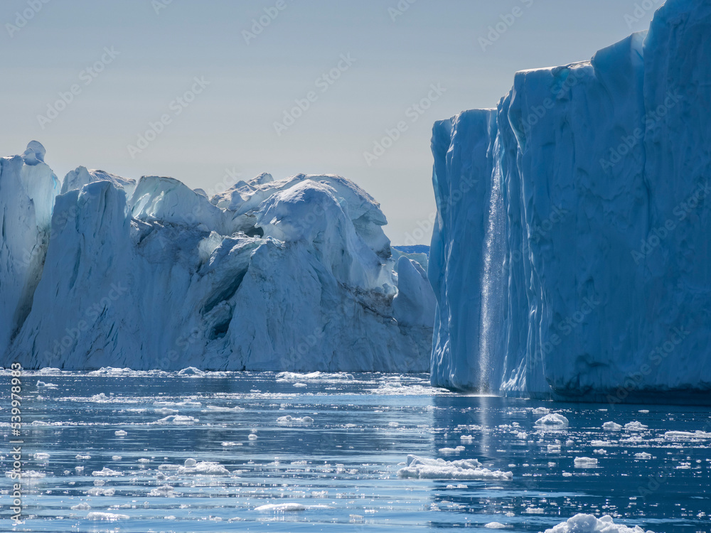 A waterfall from melting icebergs from the Ilulissat Icefjord just ...