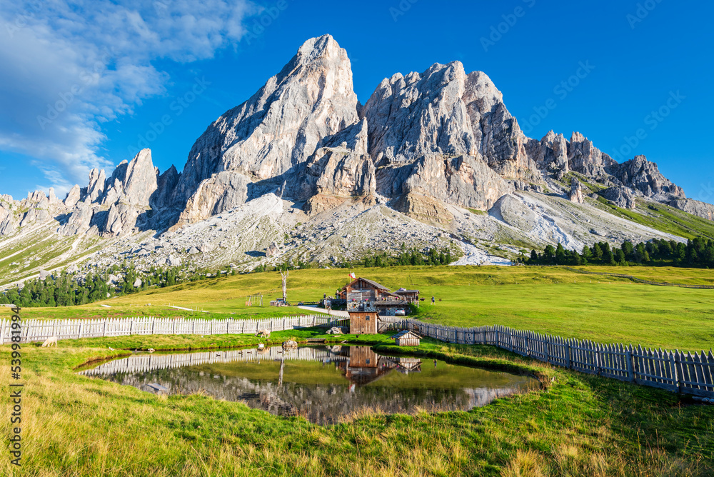 Sass de Putia and the reflection of a mountain hut in a small pond ...