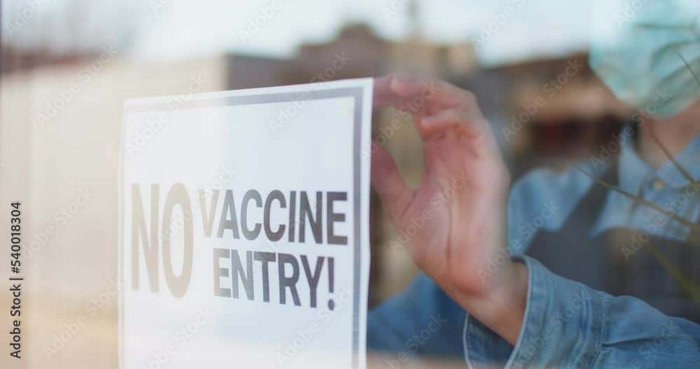 Woman wearing face mask attaching sign on the glass in pandemic time ...
