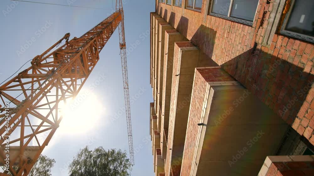Construction crane from below. Construction of a house. Sun rays ...