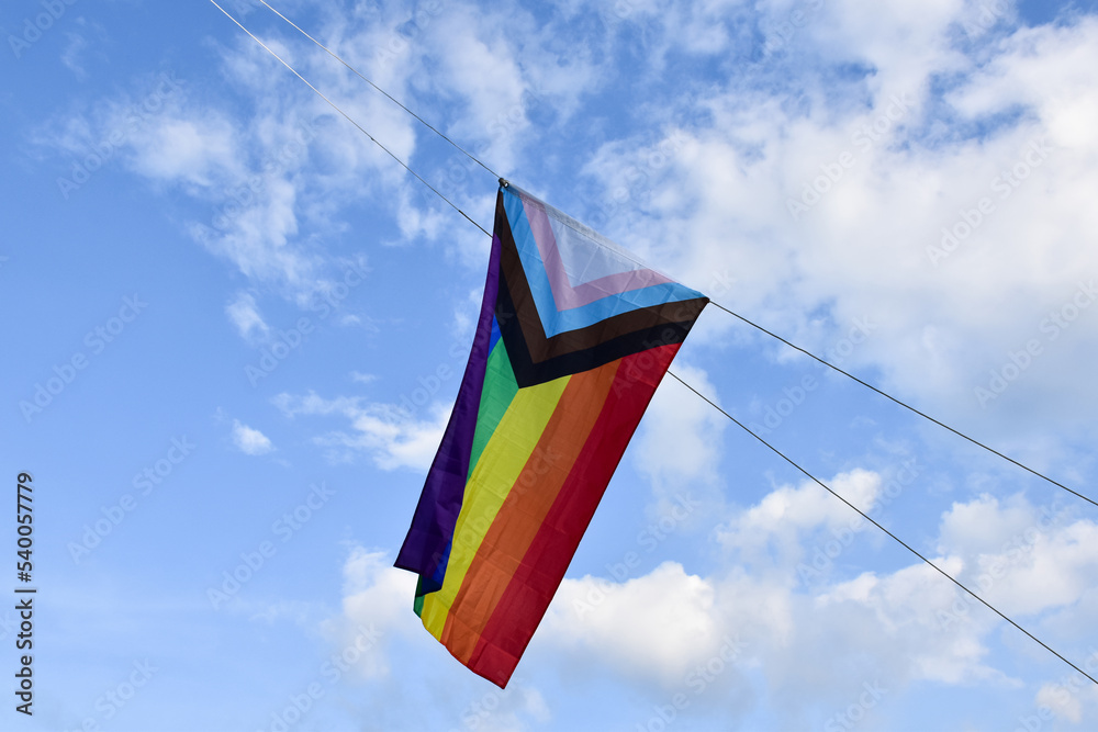 LGBTQ+ flag is tied on a rope and is being lifted to the top of the ...
