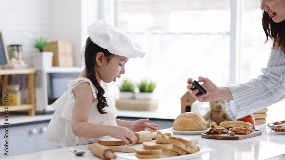 toddler girl is learning to cook bread in the kitchen with her mom with ...