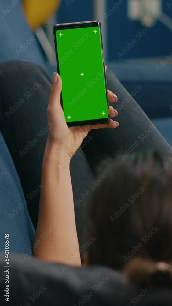 Vertical video: Freelancer lying on sofa while having online videocall on smartphone with mock ...