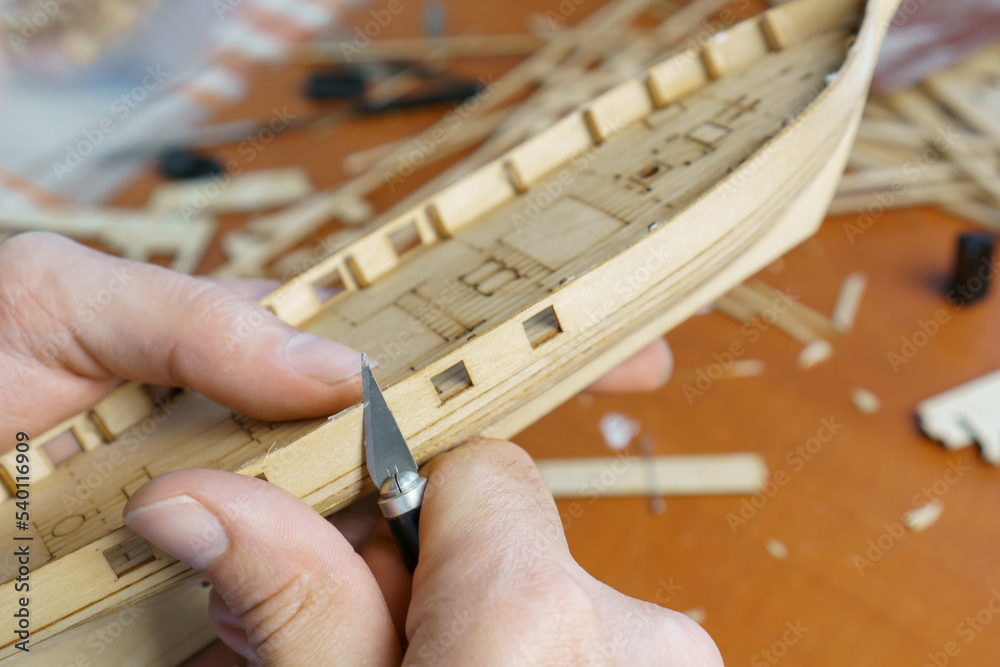 Foto de Hands of man cutting out details for ship model with clerical ...